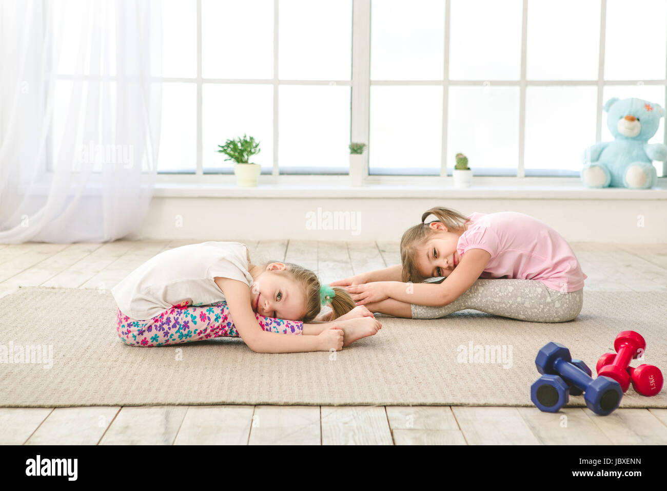 Little children sisters girls exercise together in the morning at home ...