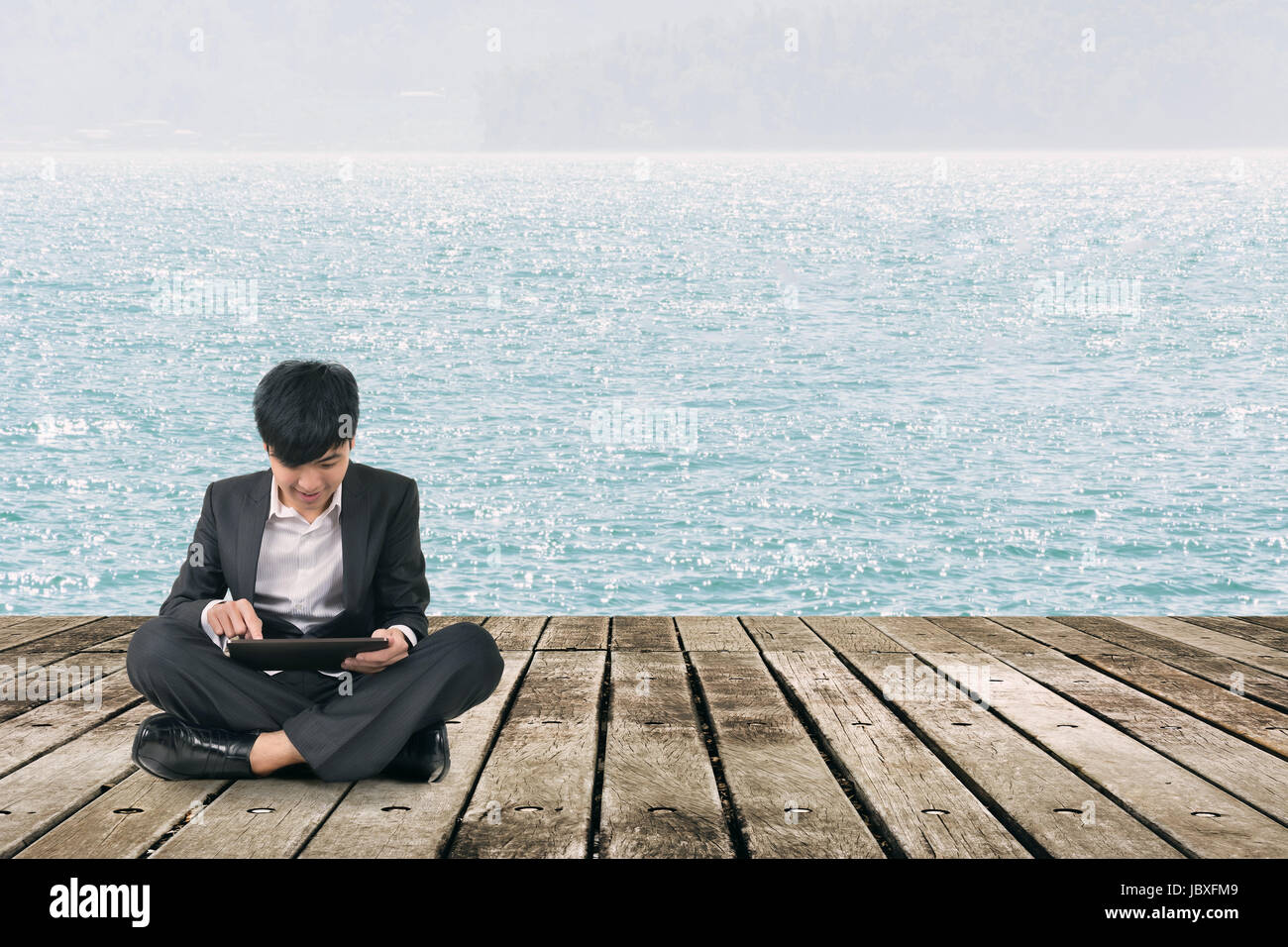 Asian business man using pad and sit on ground Stock Photo - Alamy