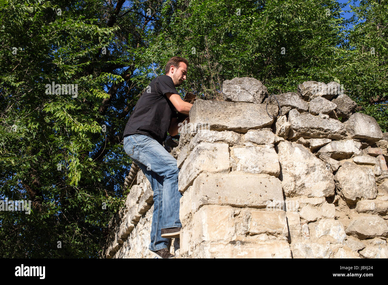 Man and a city. The young man is climbing on the wall Stock Photo - Alamy