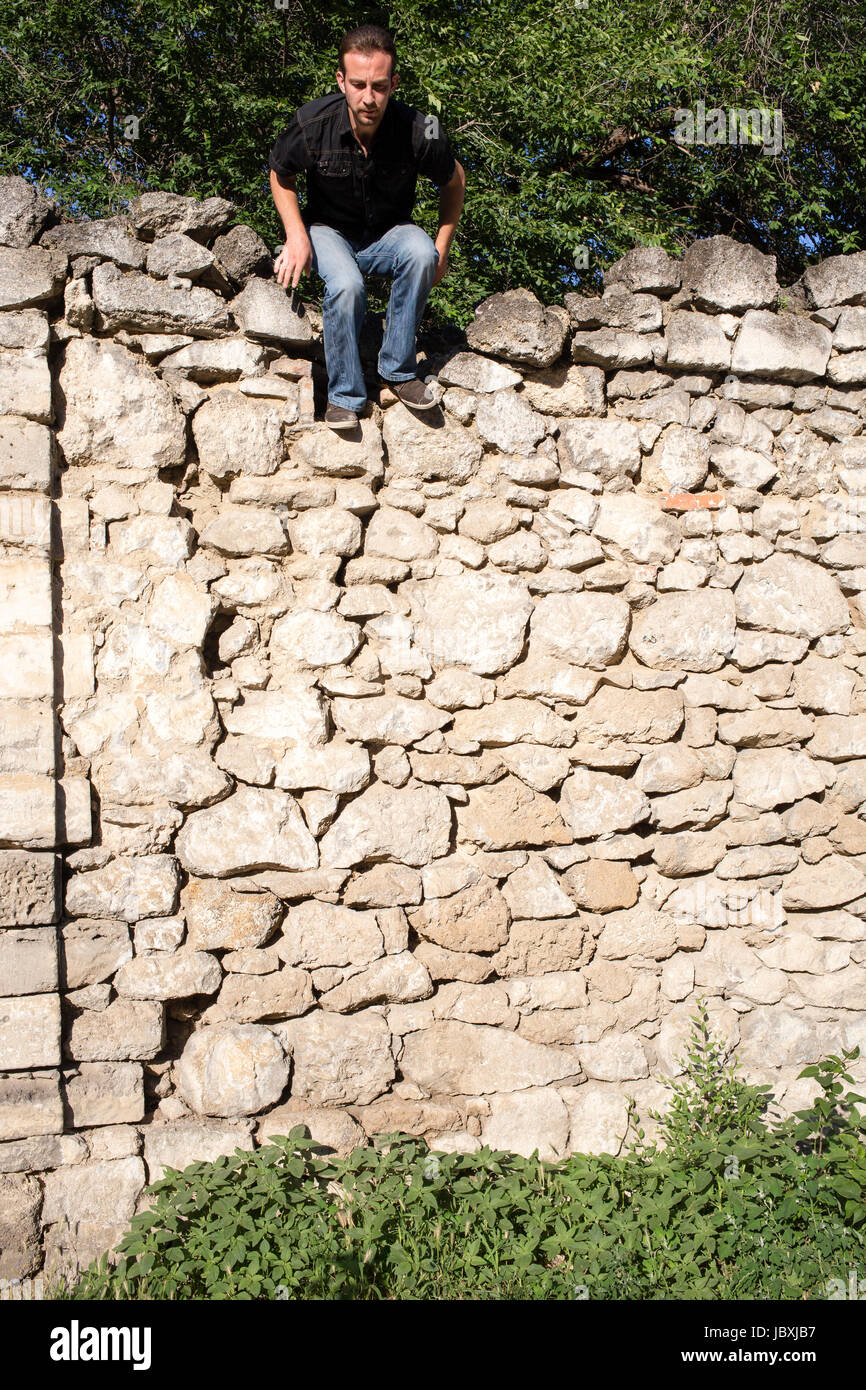 Man and a city. The young man is siting on the wall Stock Photo - Alamy