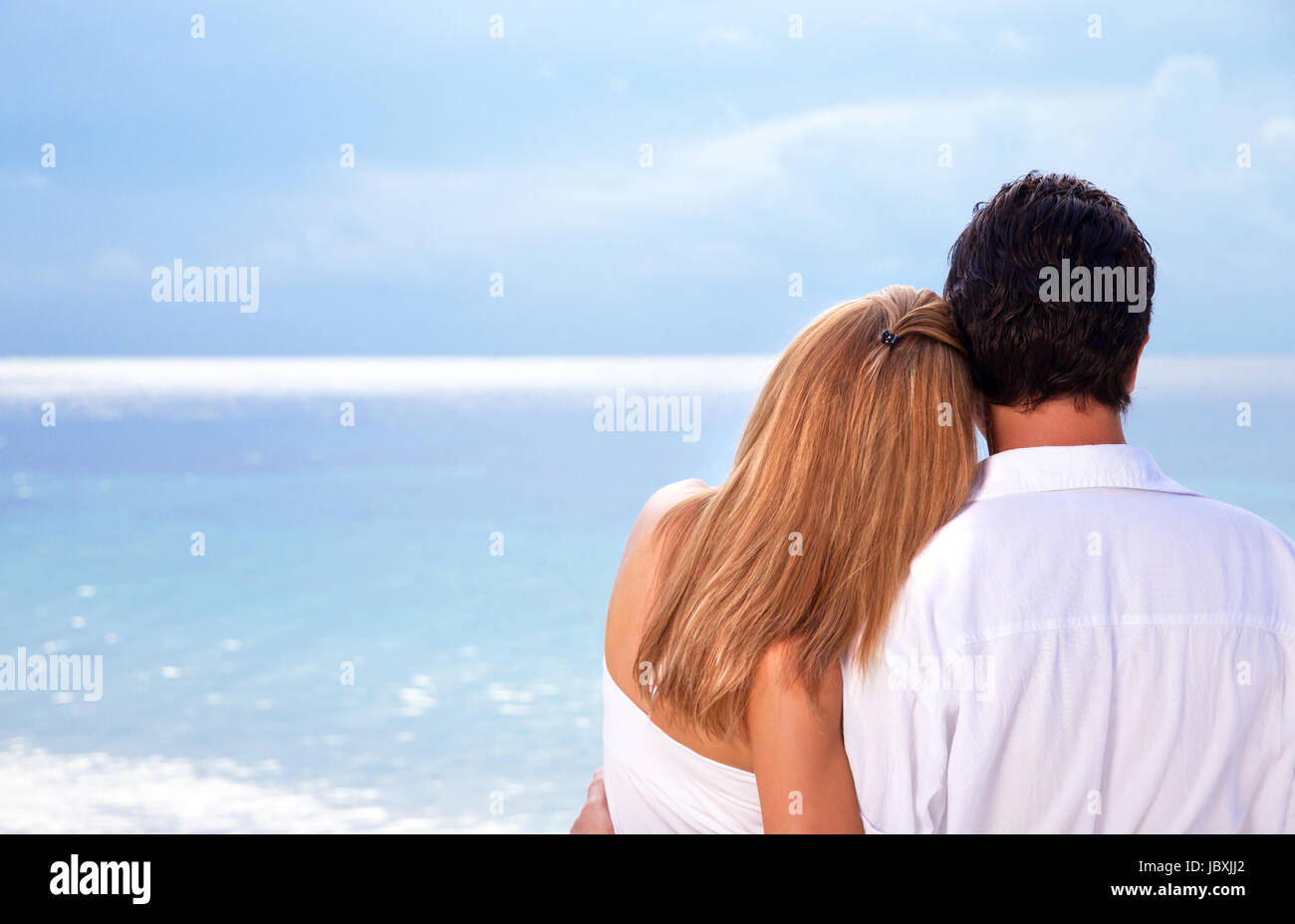 Rear view of young couple hugging on the beach, honeymoon on Maldives ...