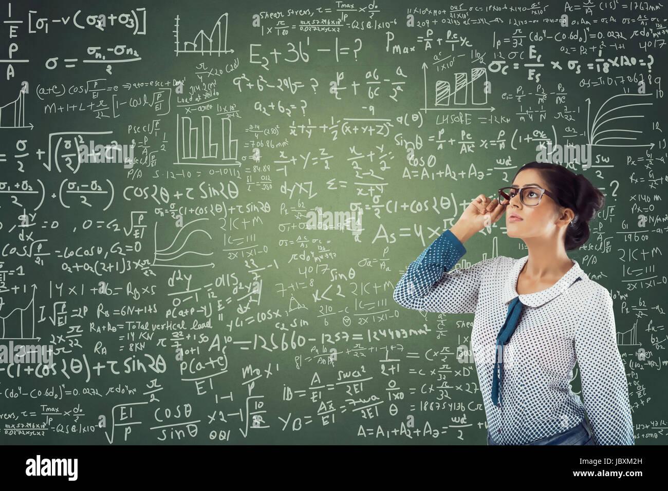 Portrait of businesswoman with arms crossed in front of chalkboard with ...