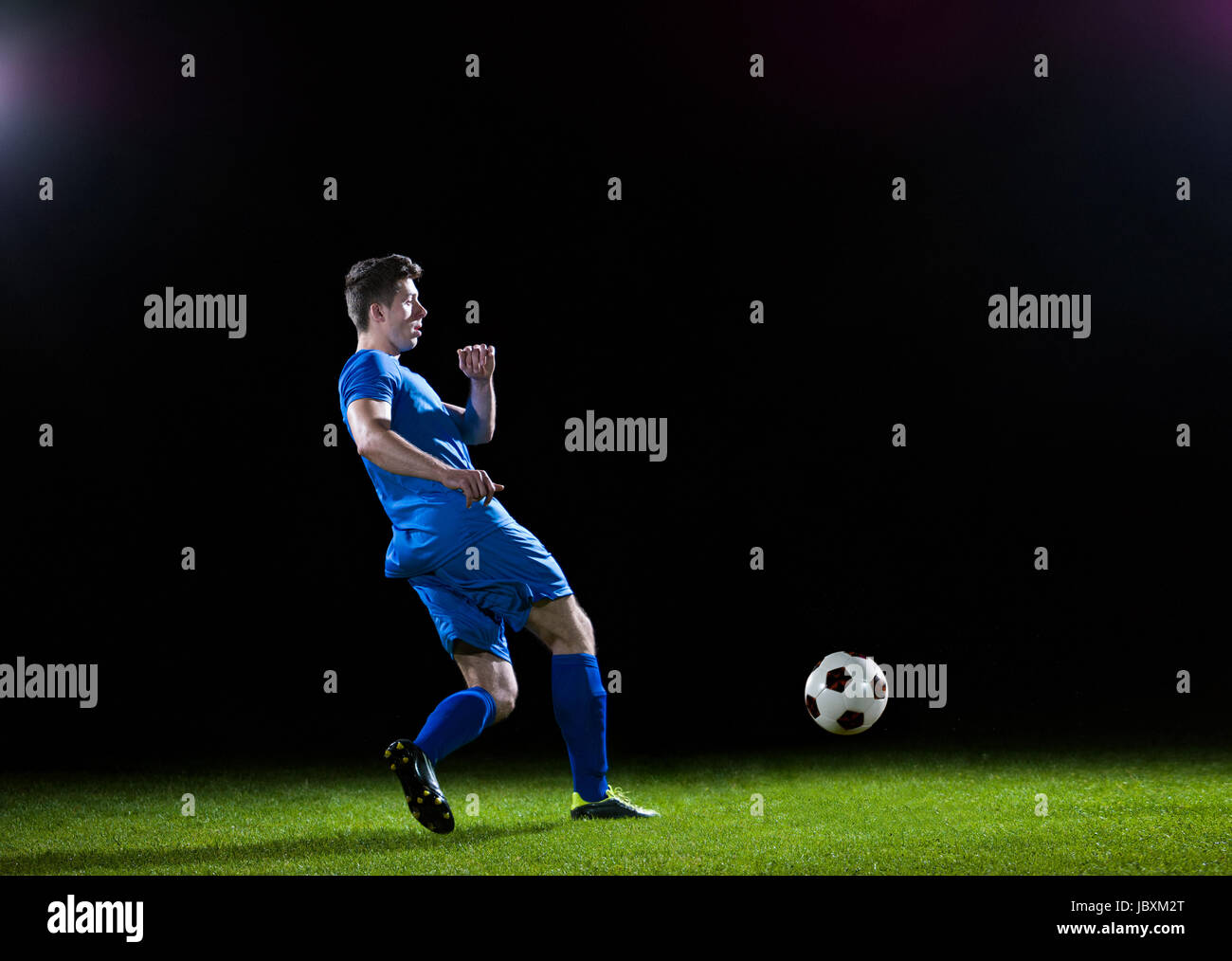 soccer player doing kick with ball on football stadium field isolated ...