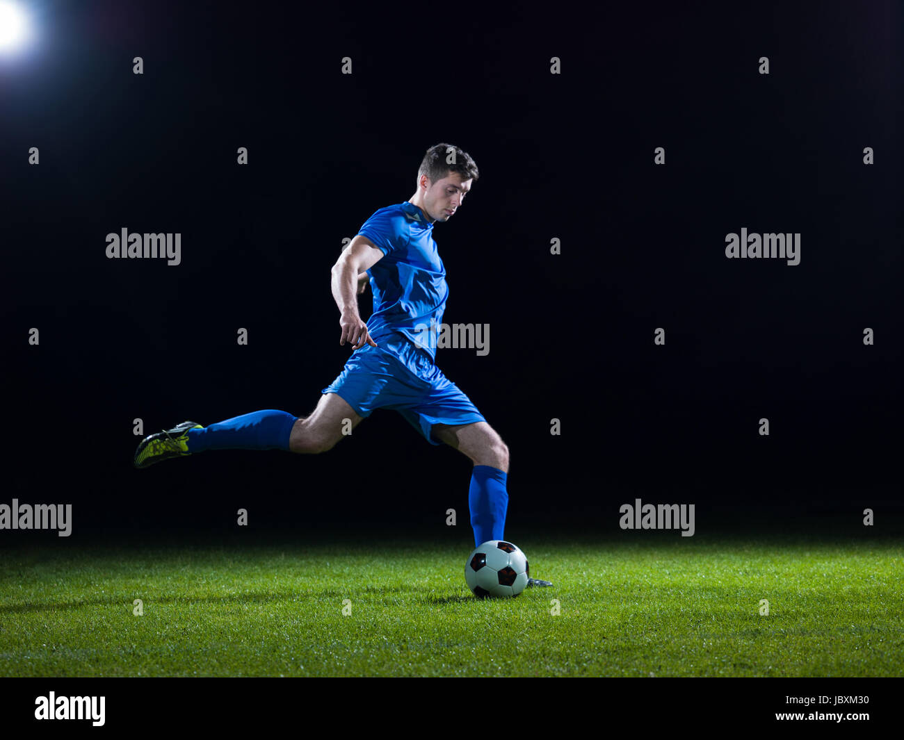 soccer player doing kick with ball on football stadium field isolated ...