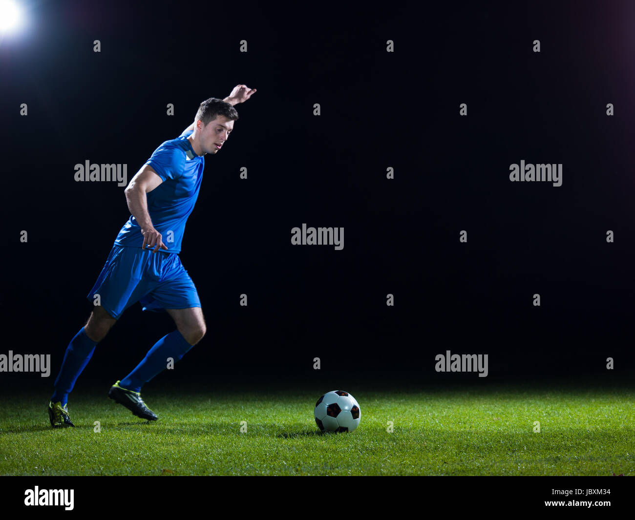 soccer player doing kick with ball on football stadium field isolated ...