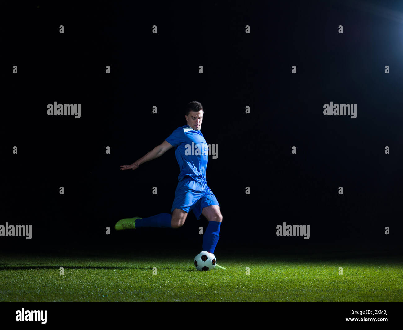 soccer player doing kick with ball on football stadium field isolated ...