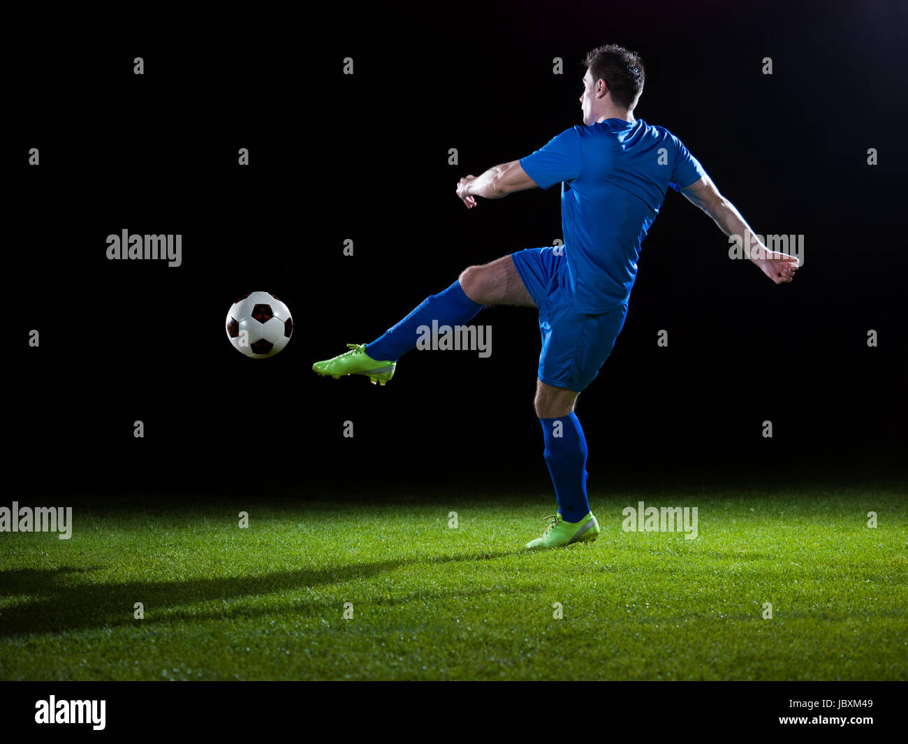 soccer player doing kick with ball on football stadium field isolated ...