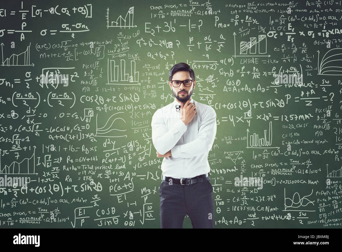 Portrait of businessman with arms crossed in front of chalkboard with ...