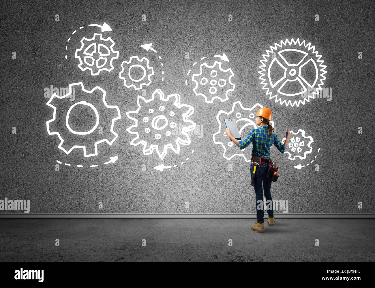 Back view of engineer woman in hardhat and sketched concept of teamwork ...