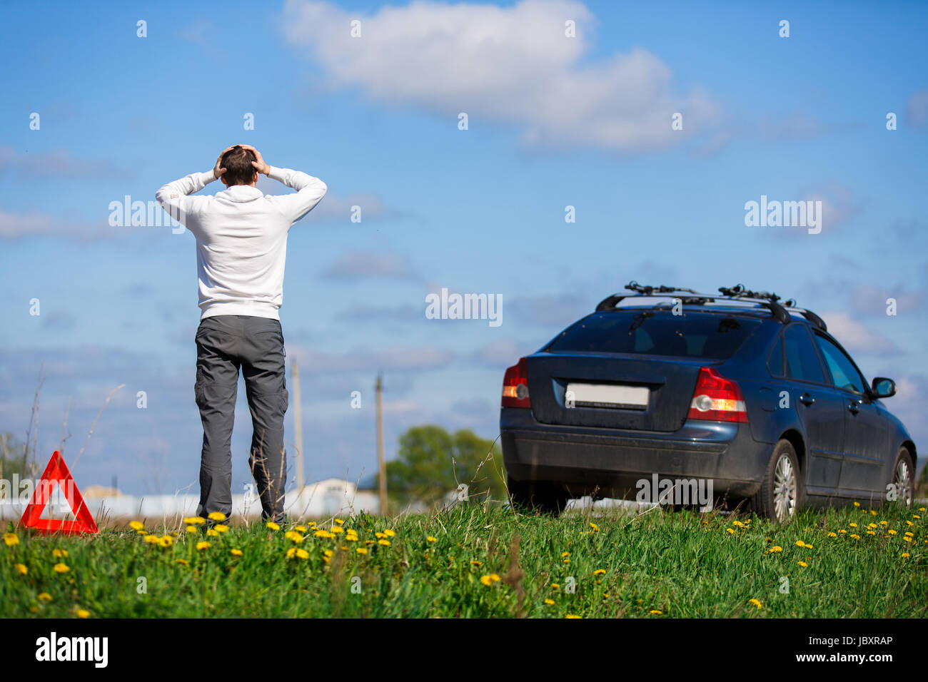 Man with hands against head in background of broken car and warning red ...