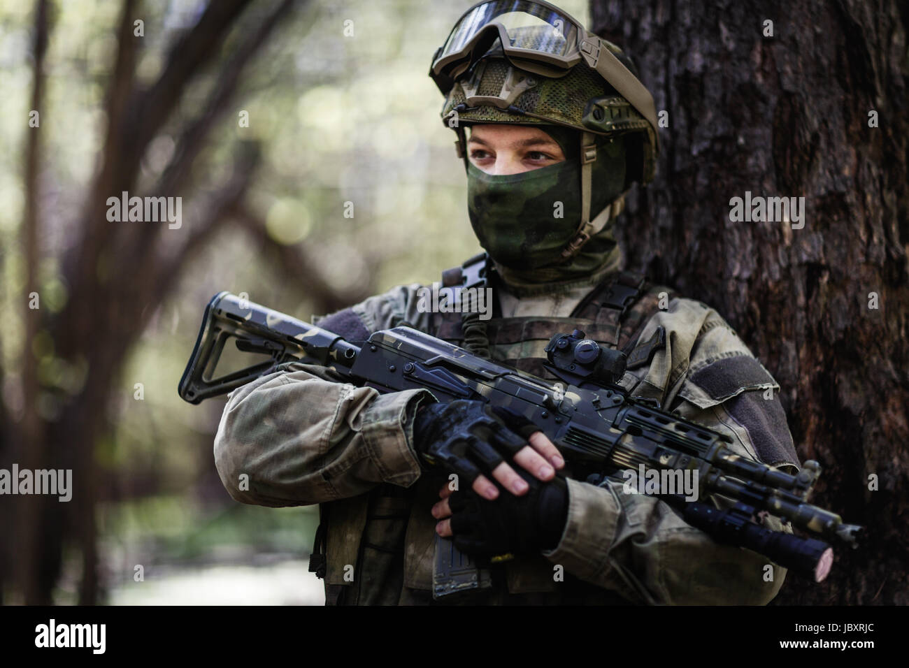 Portrait of soldier with submachine gun standing in woods during day ...