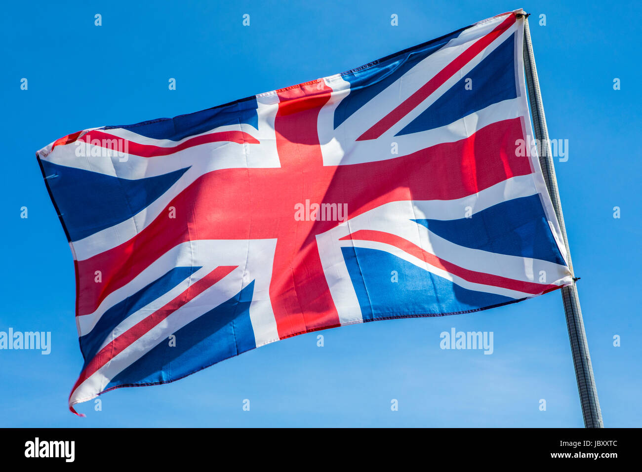 A Union Flag flying proudly under a clear blue sky Stock Photo - Alamy