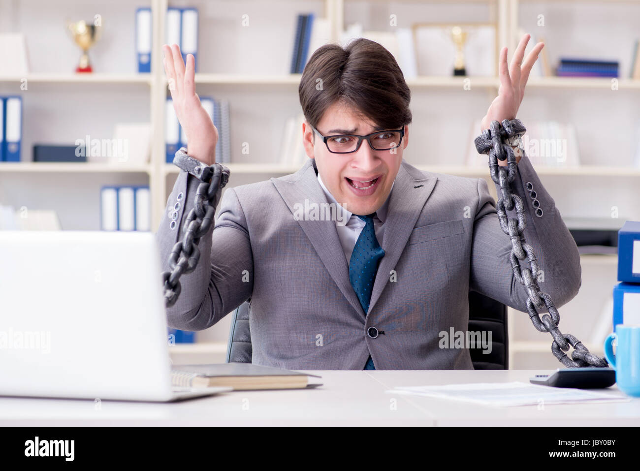 Businessman tied with chains to his work Stock Photo - Alamy
