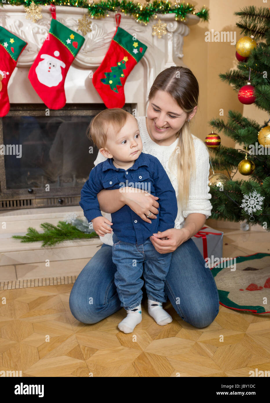 Happy smiling mother cuddling her baby boy at Christmas tree Stock ...