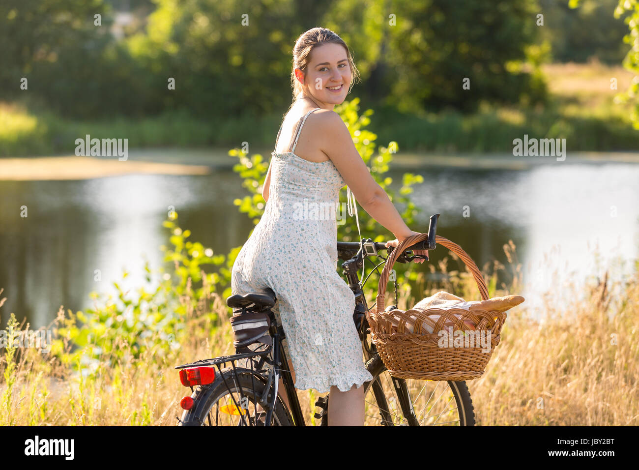 Portrait of beautiful young woman in short dress riding on bicycle by ...