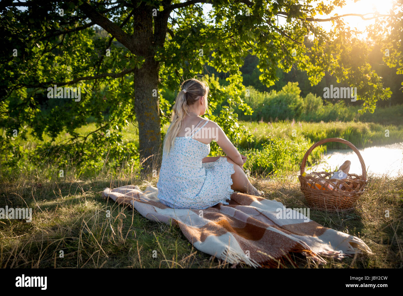Toned image of beautiful lonely woman relaxing under big tree and ...