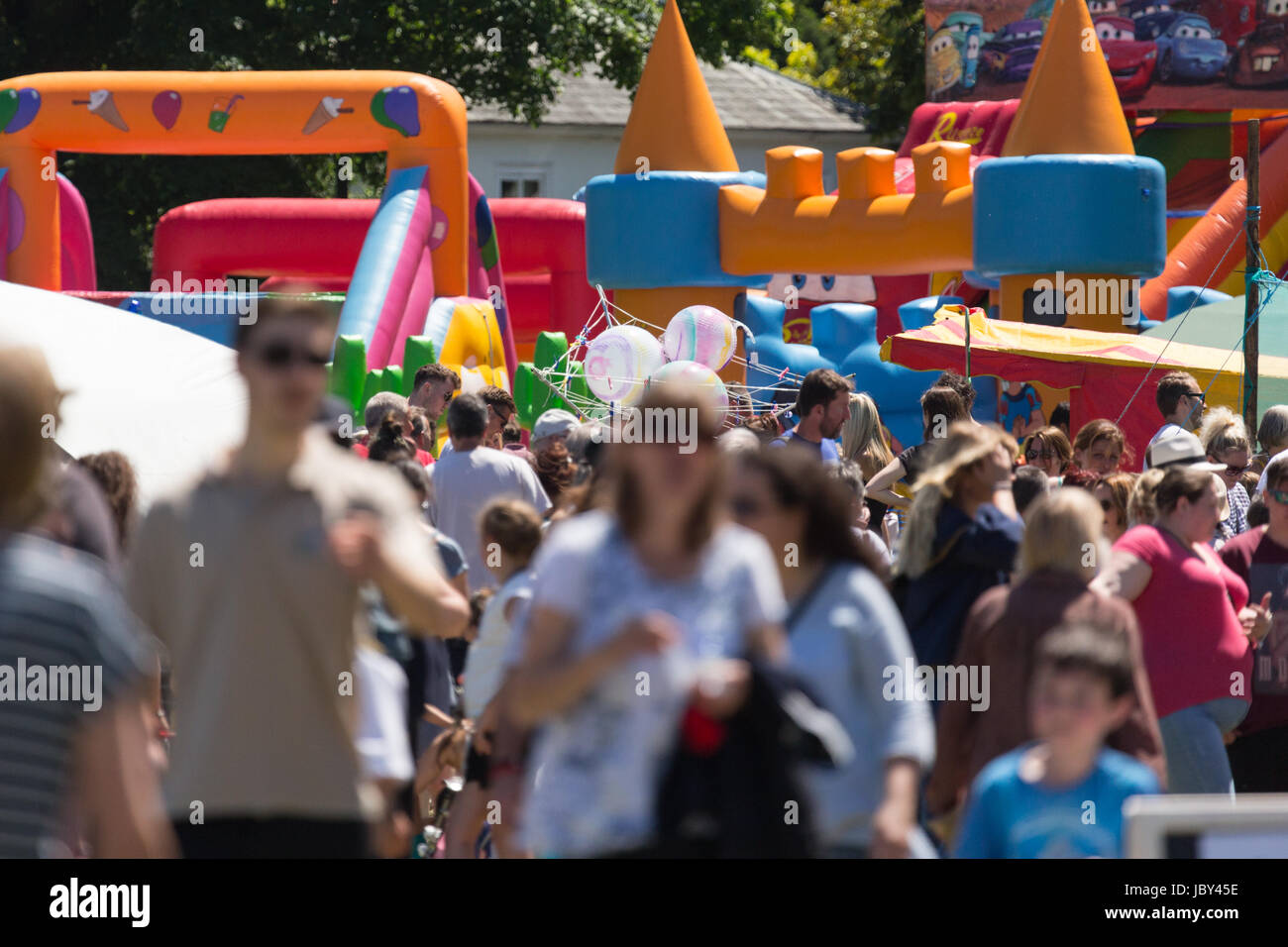 Crowds of people walking to and from rides, bouncy castle & stalls on ...