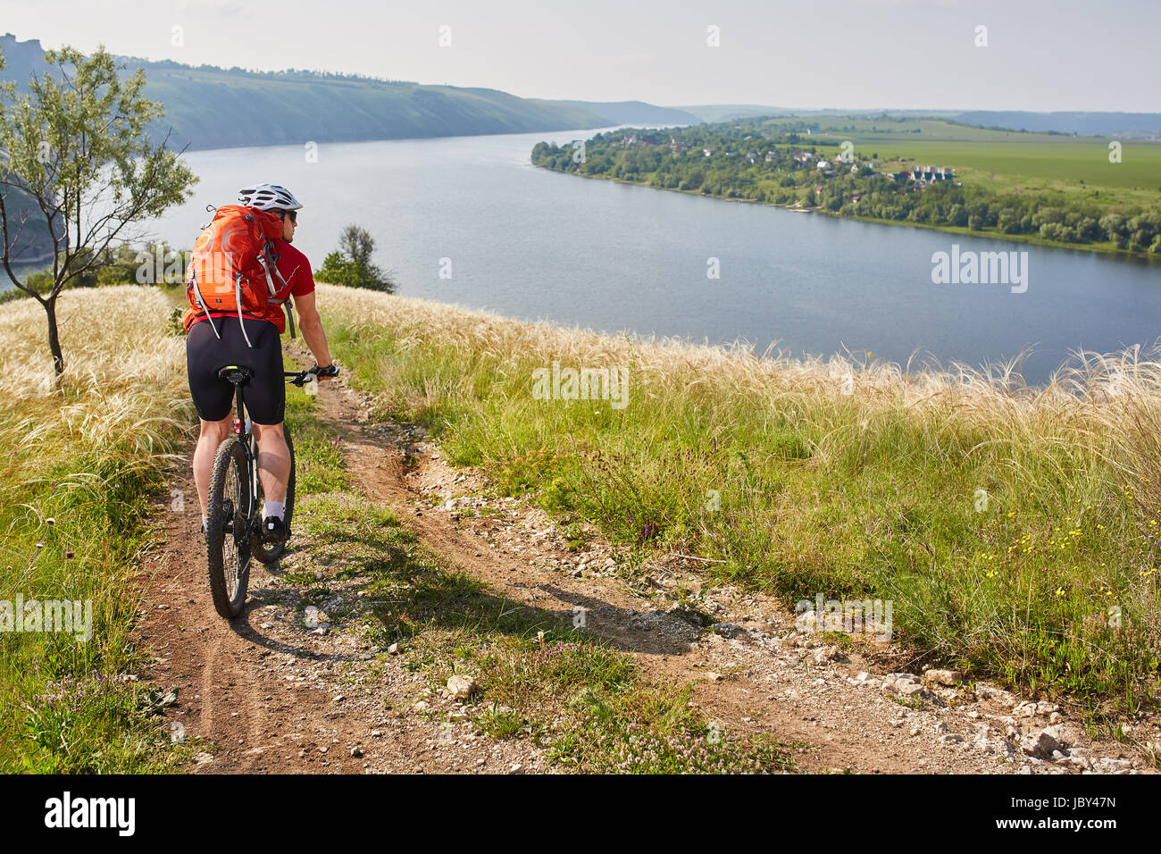 Rear view of the young attractive cyclist riding mountain bike in the ...