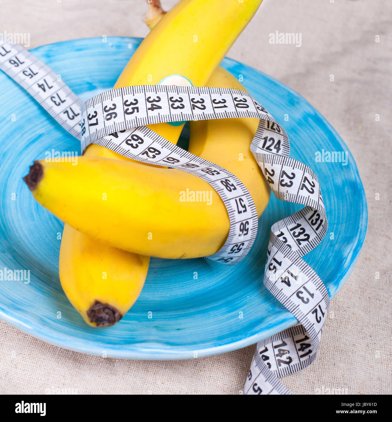 Diet concept. Bananas with measuring tape on blue plate Stock Photo - Alamy