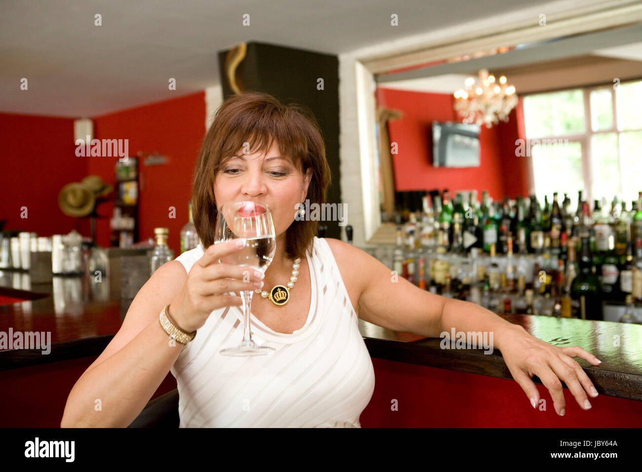 Frau in weißen Kleid sitzt an der Theke einer Bar Stock Photo - Alamy