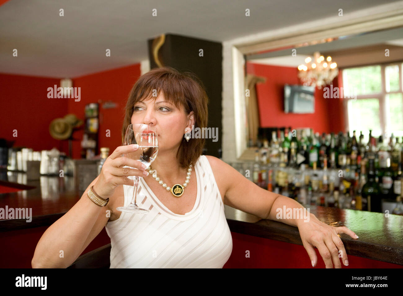 Frau in weißen Kleid sitzt an der Theke einer Bar Stock Photo - Alamy