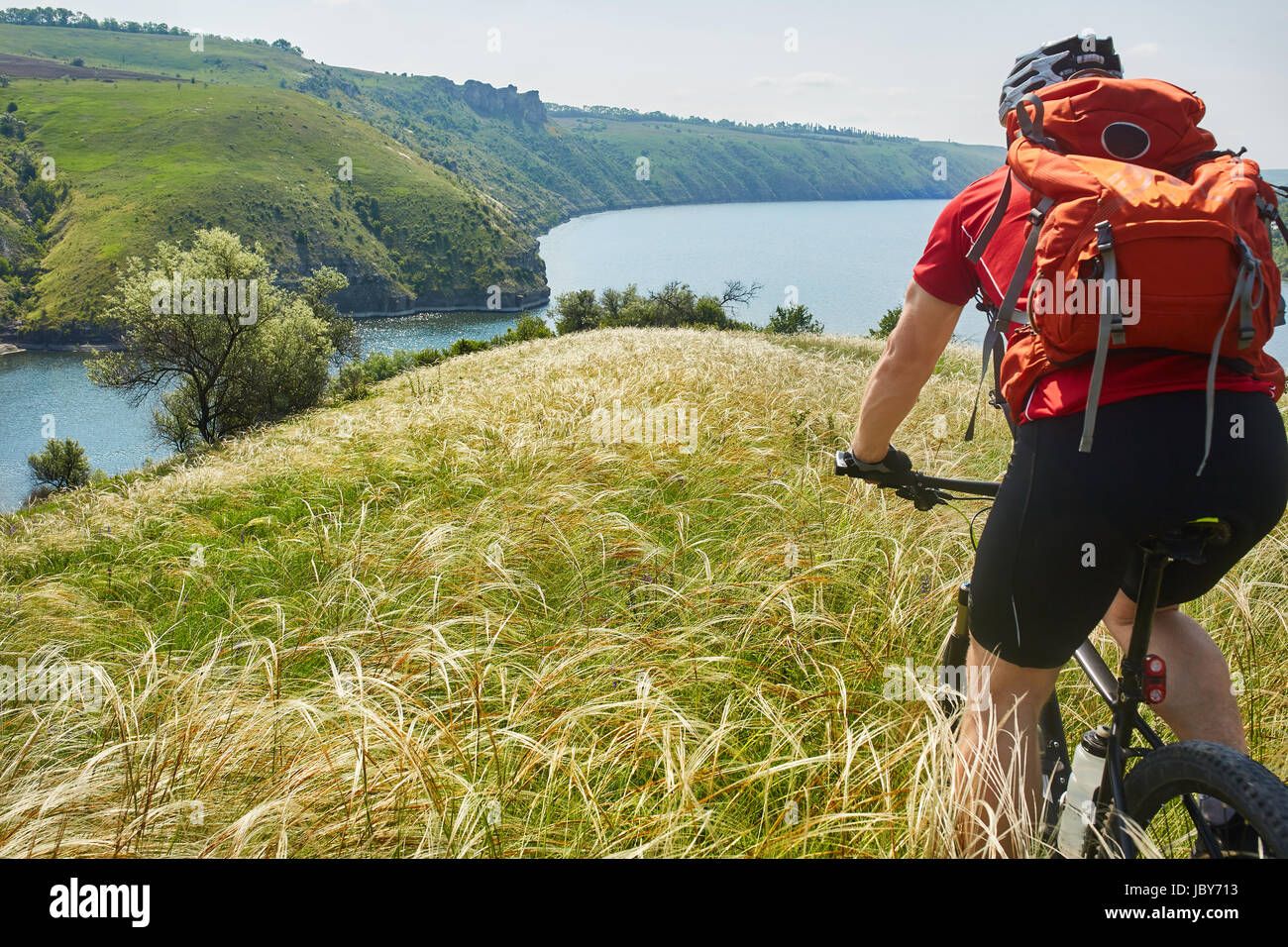 Rear view and close-up of the young cyclist riding bike on the summer ...