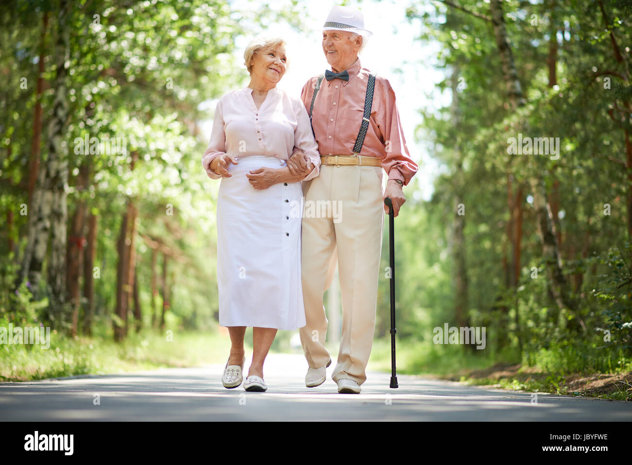 Happy seniors talking while taking a walk in the park Stock Photo - Alamy