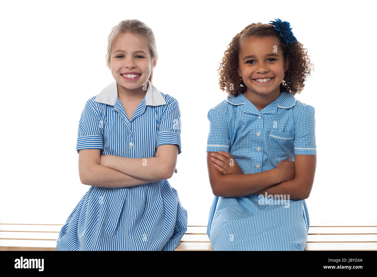 Smiling school girls sitting in bench, arms folded Stock Photo - Alamy