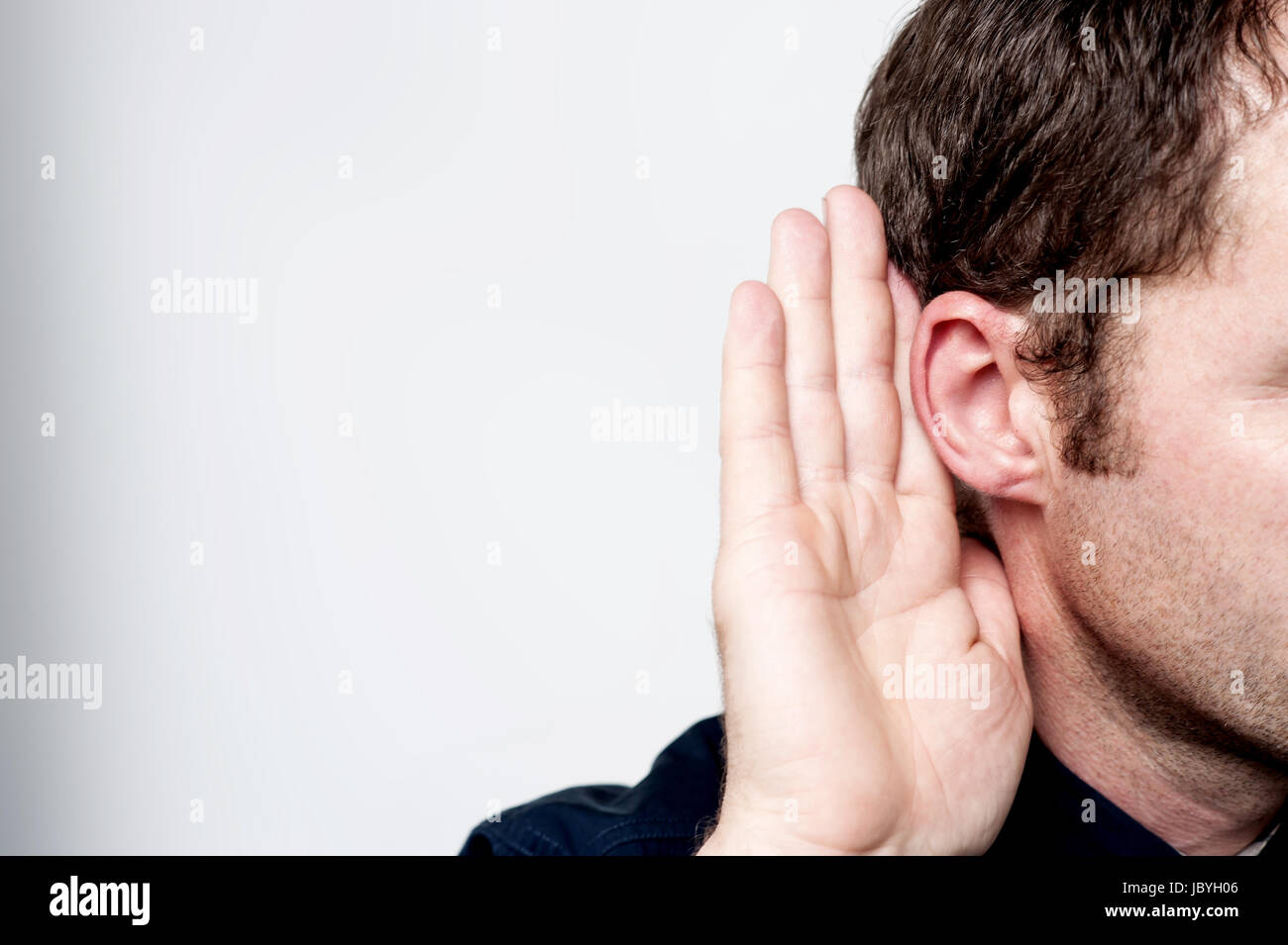 Listening male holds his hand near his ear Stock Photo - Alamy