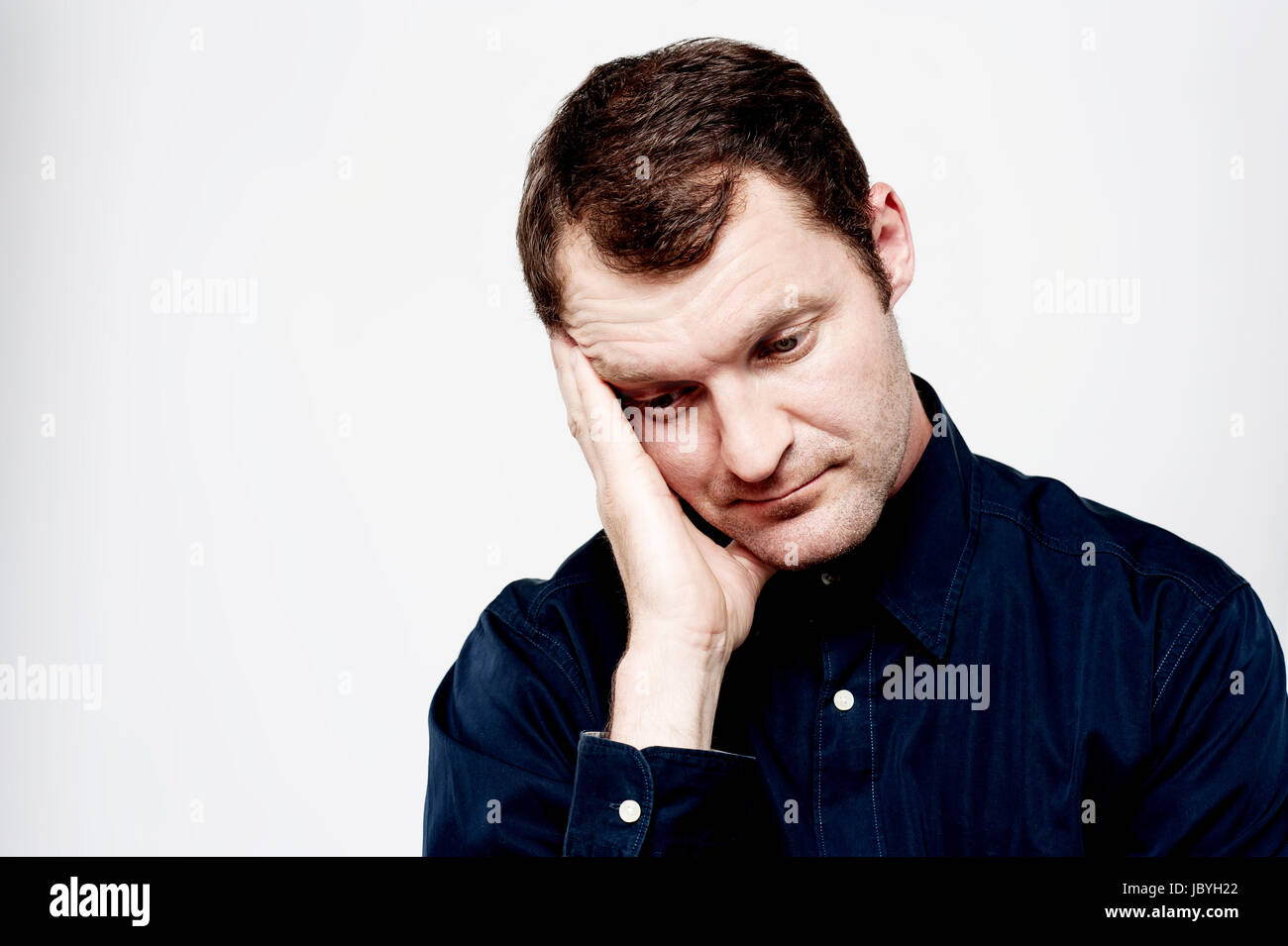 Disappointed man resting his face on hands, looking down Stock Photo ...
