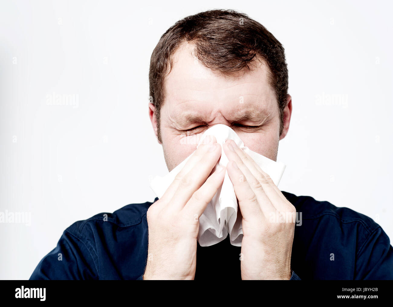 Man blowing his nose in a tissue Stock Photo - Alamy