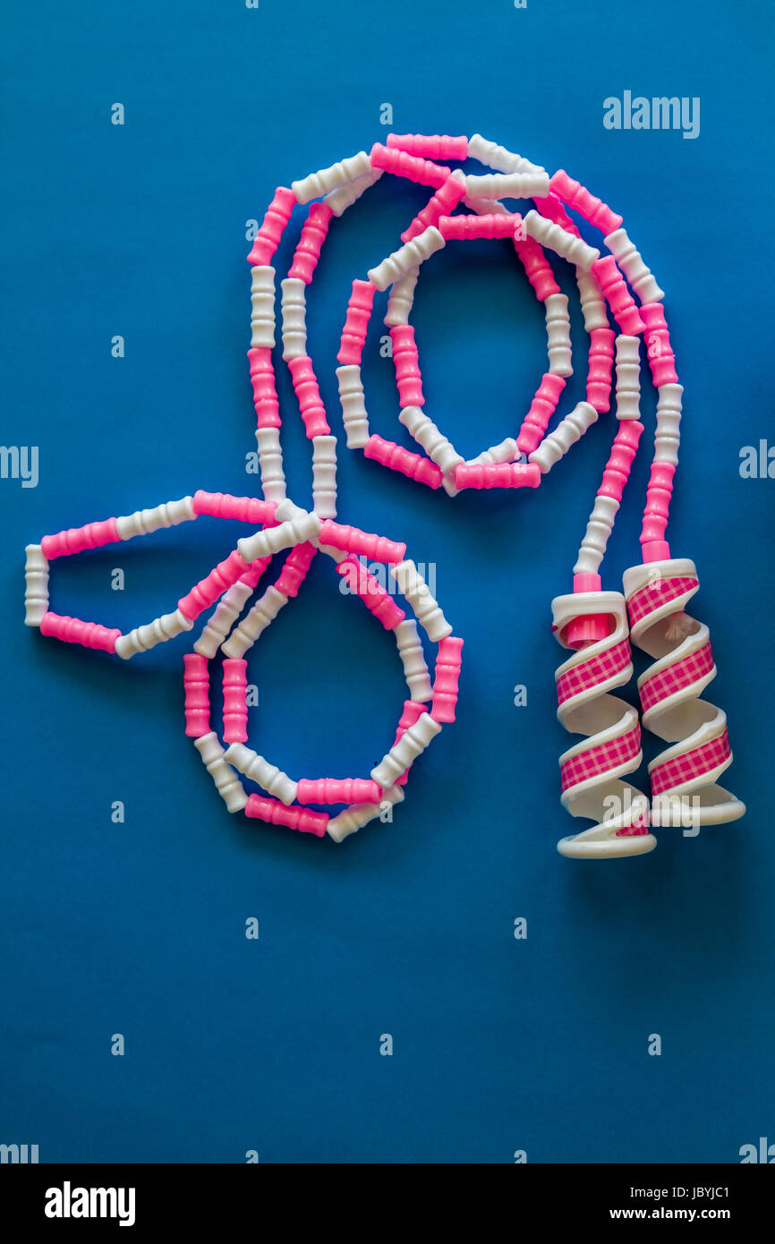 Pink and white toy jump rope on a blue background Stock Photo - Alamy