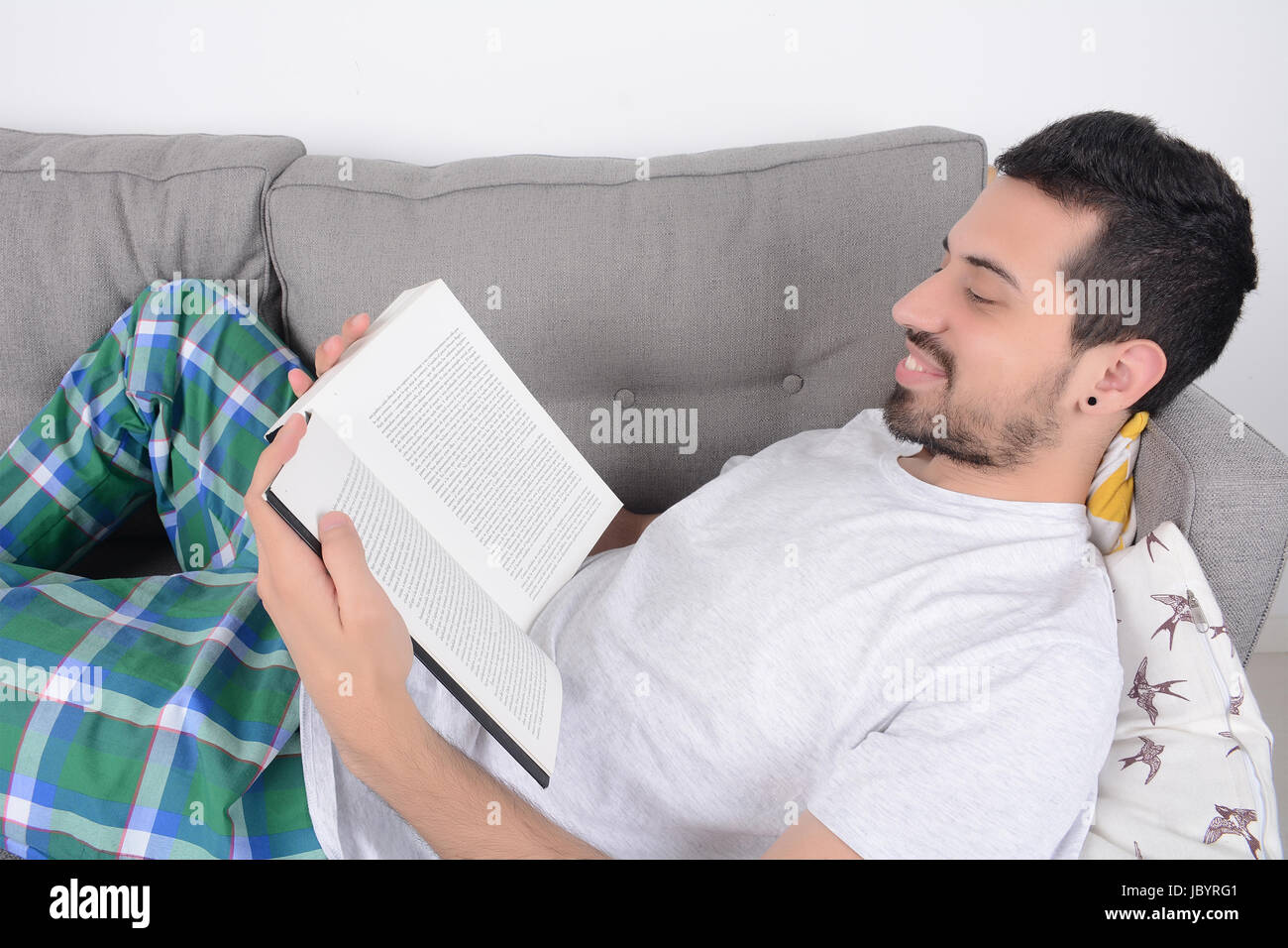 Attractive young man relaxed and reading a book. Indoors Stock Photo ...