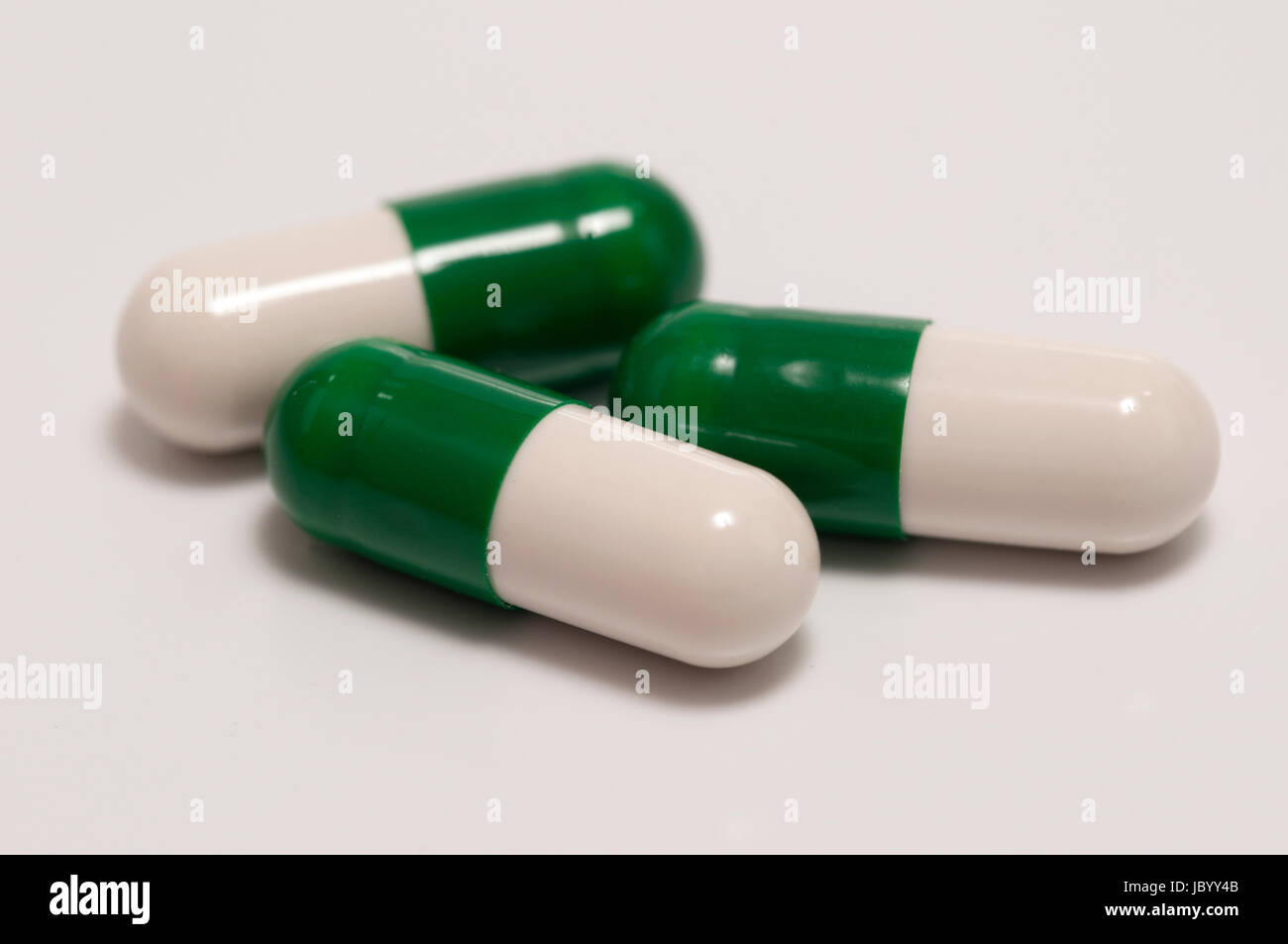 Three capsules or pills on white background Stock Photo - Alamy