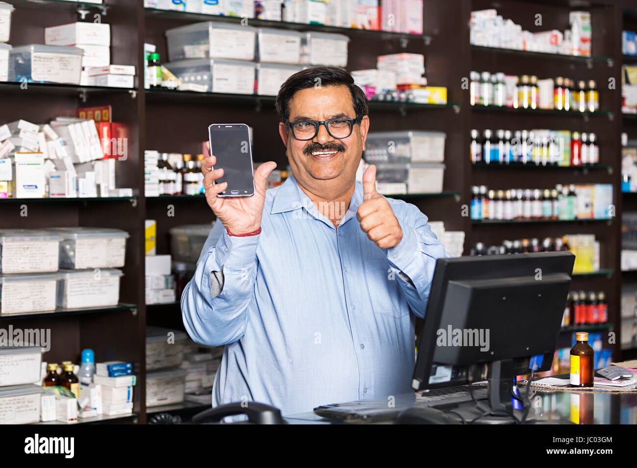 1 Indian Shopkeeper Man Showing Thumbs up With Mobile Phone In Chemist ...
