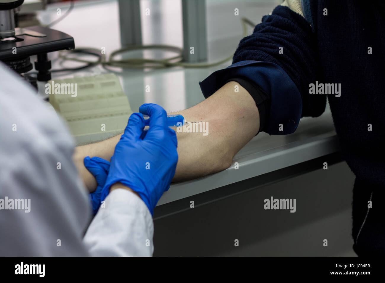 Doctor or scientist inject a needle in patient's arm Stock Photo - Alamy