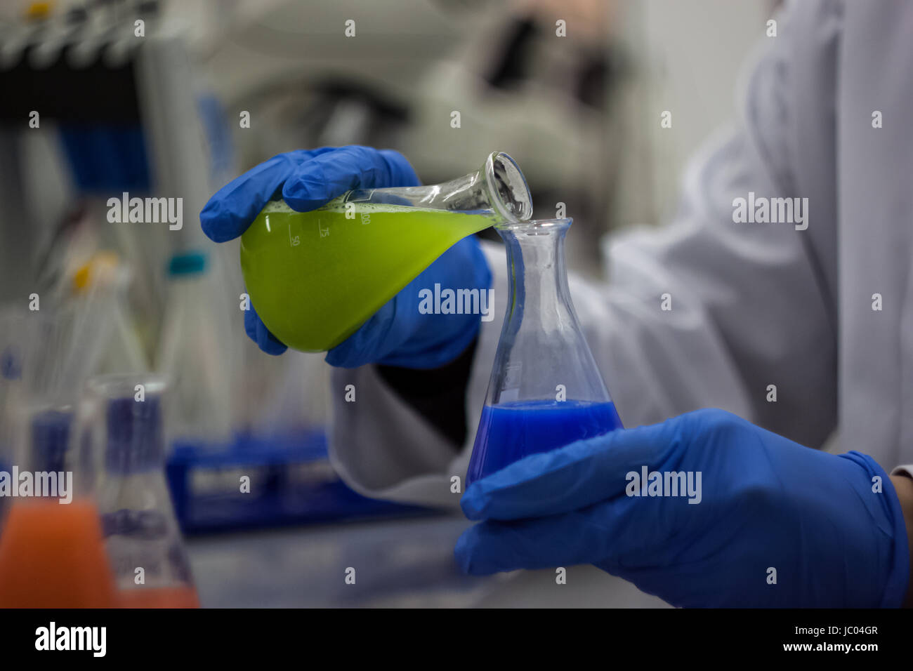 Researcher or scientist or phd student mixing green and blue chemical ...