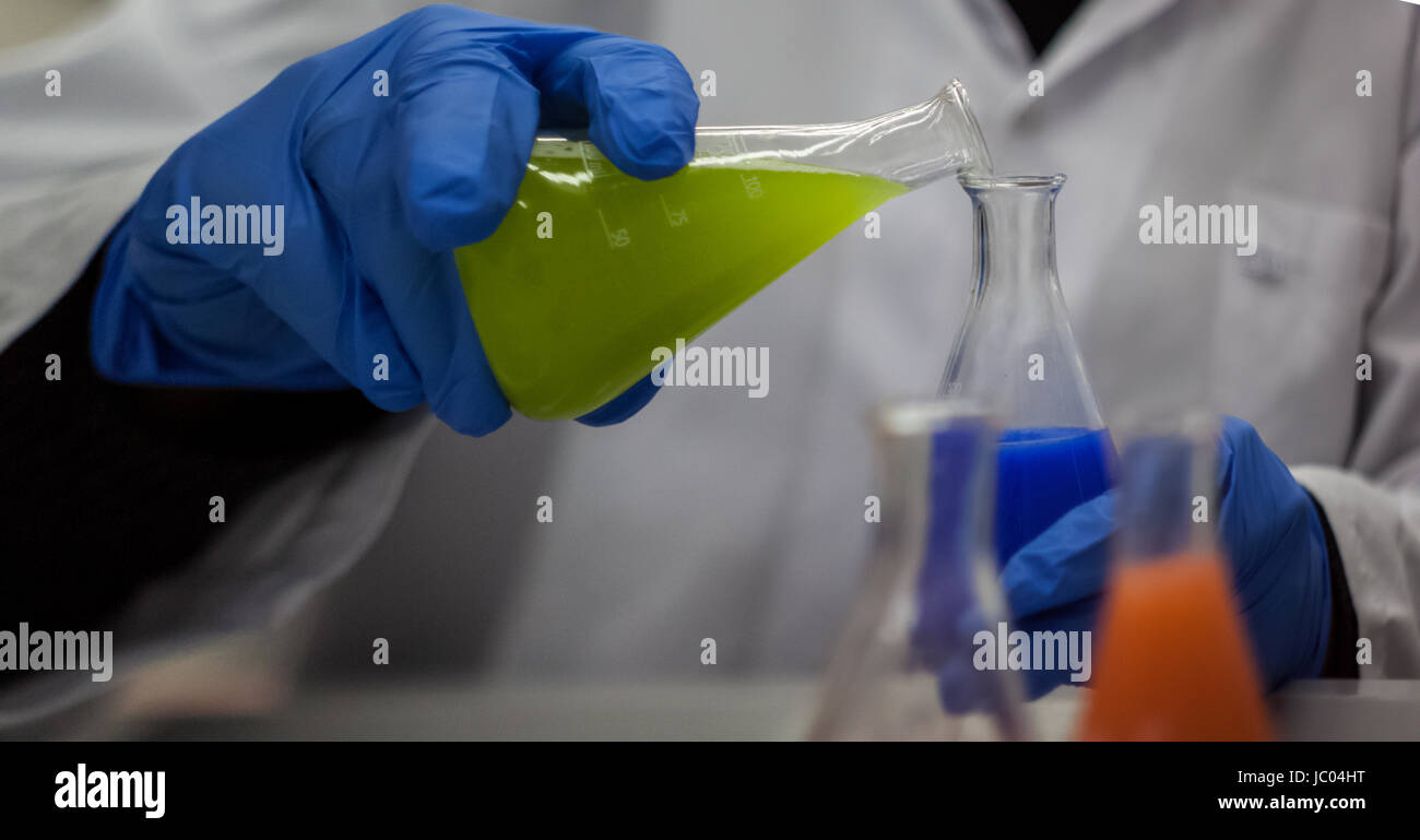 Researcher or scientist or phd student mixing green and blue chemical ...