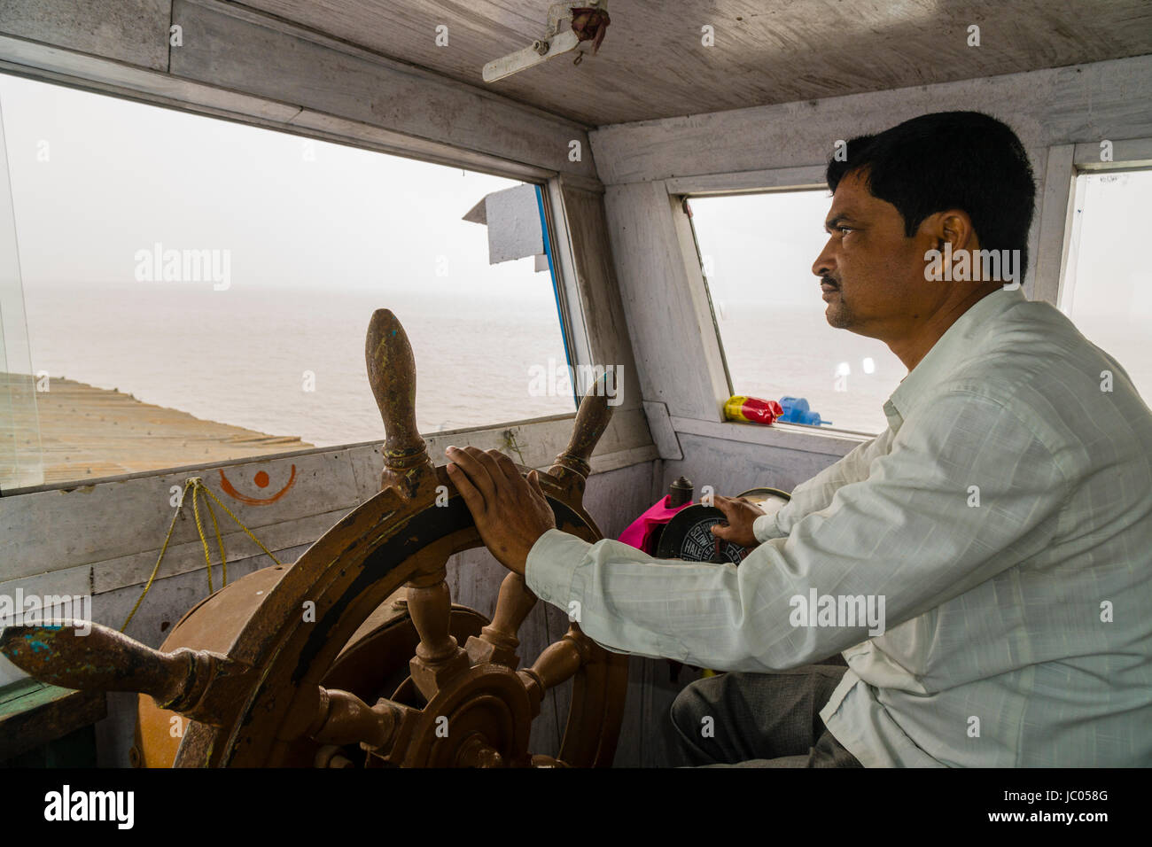 The skipper of a ferry boat full with pilgrims is driving for Ganga ...