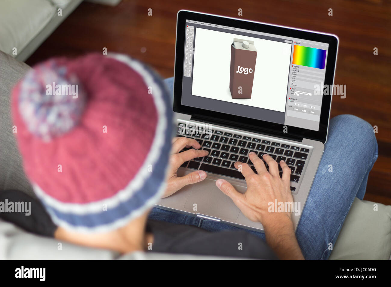 Hipster designer on sofa designing packaging. All screen graphics are ...