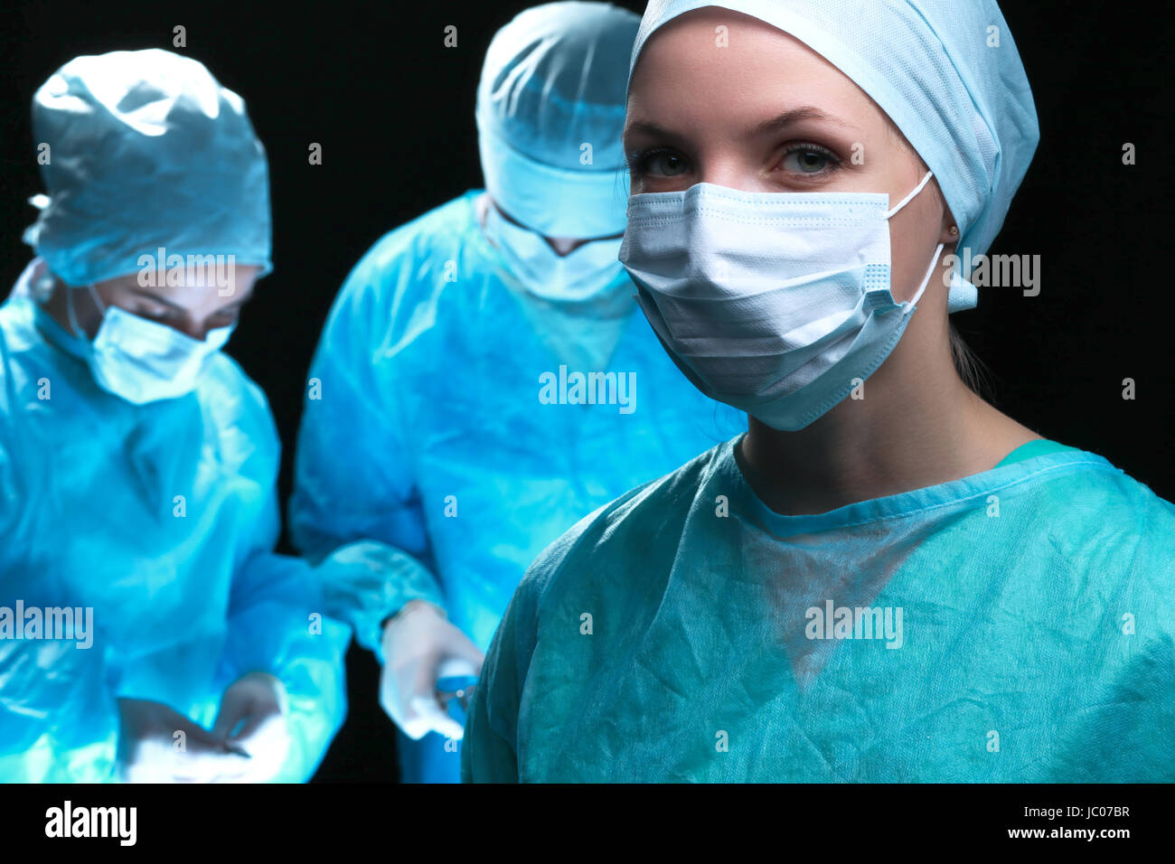 Three surgeons at work operating in surgical theater saving patient and ...