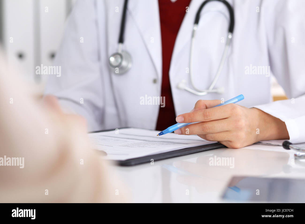 Close up of a female doctor filling up an application form while ...