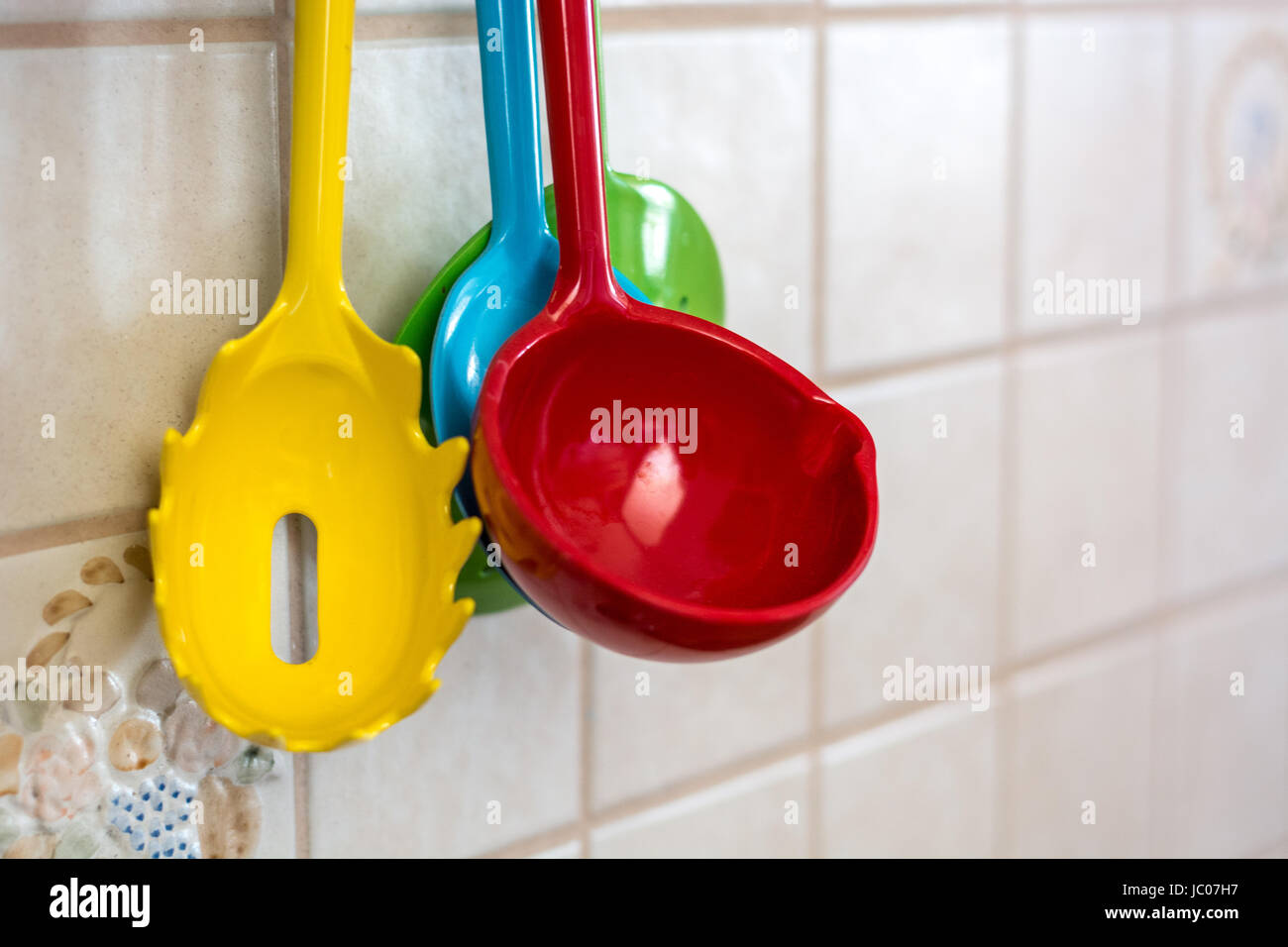 Colorful ladles hanging on a wall in the kitchen Stock Photo - Alamy