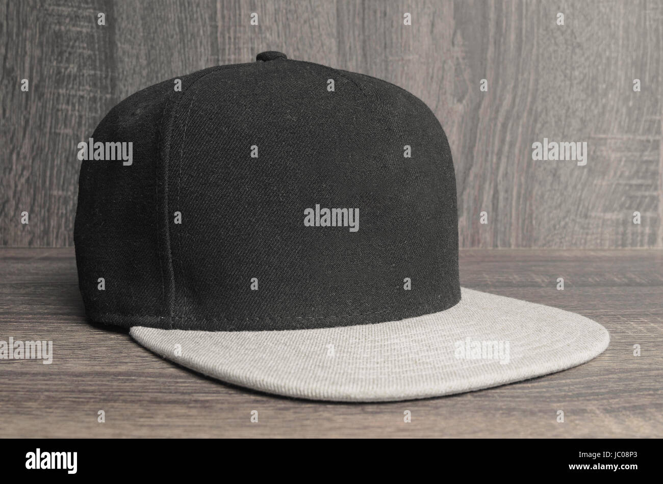 Black cap with light gray flap on a wooden background. Straight flap ...