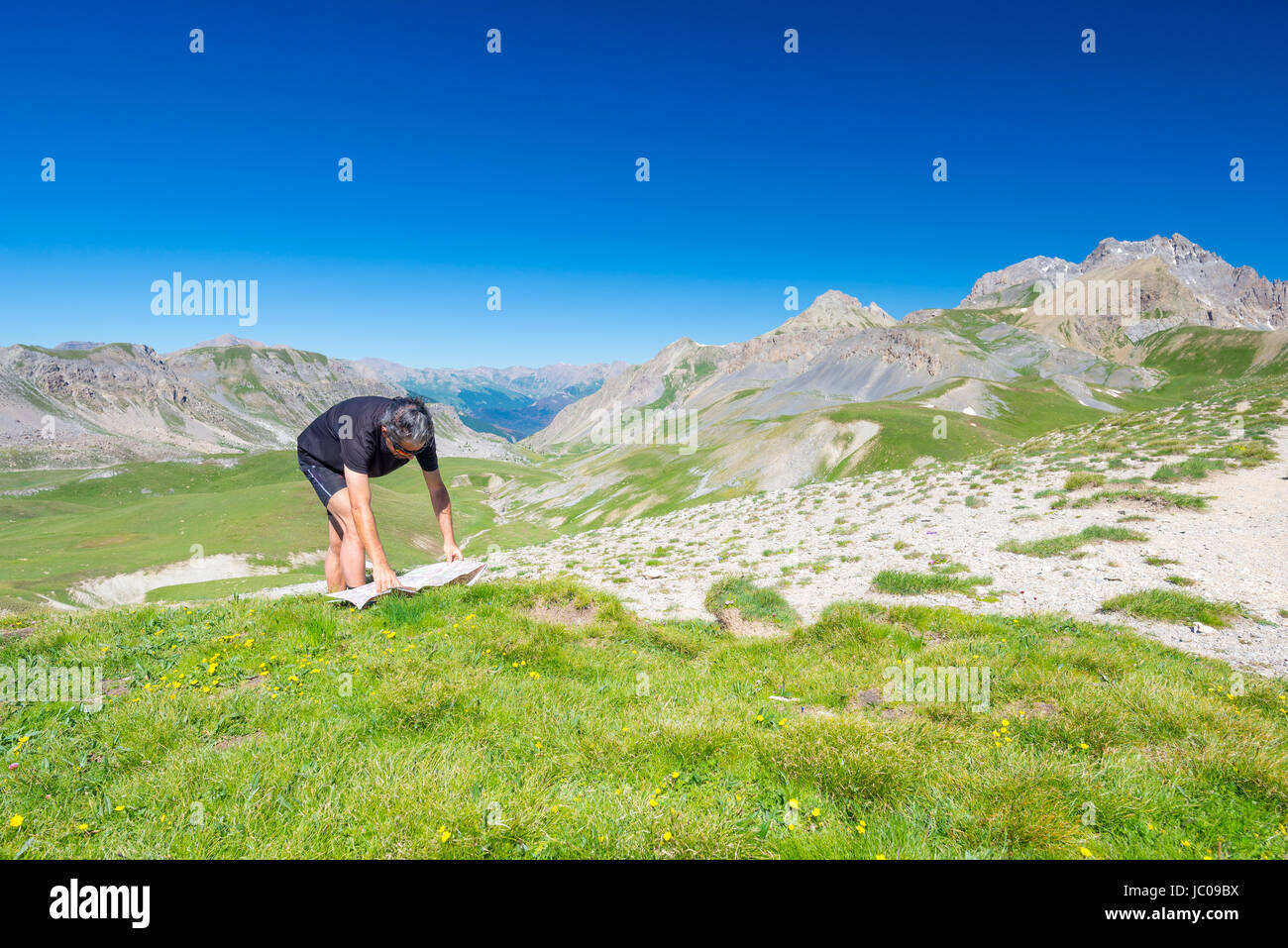 Hiker reading trekking map while resting at panoramic mountain spot ...