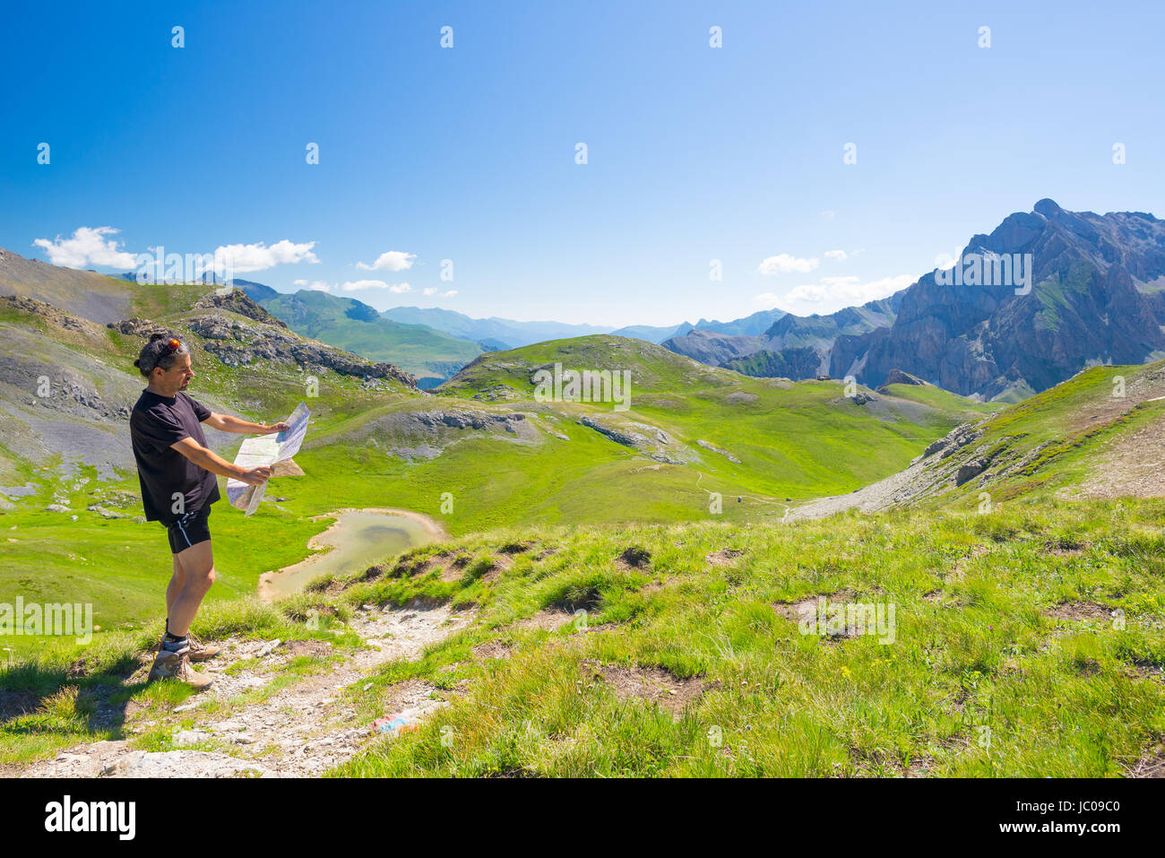 Hiker reading trekking map while resting at panoramic mountain spot ...