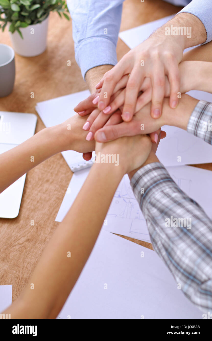 Business people joining hands over table Stock Photo - Alamy