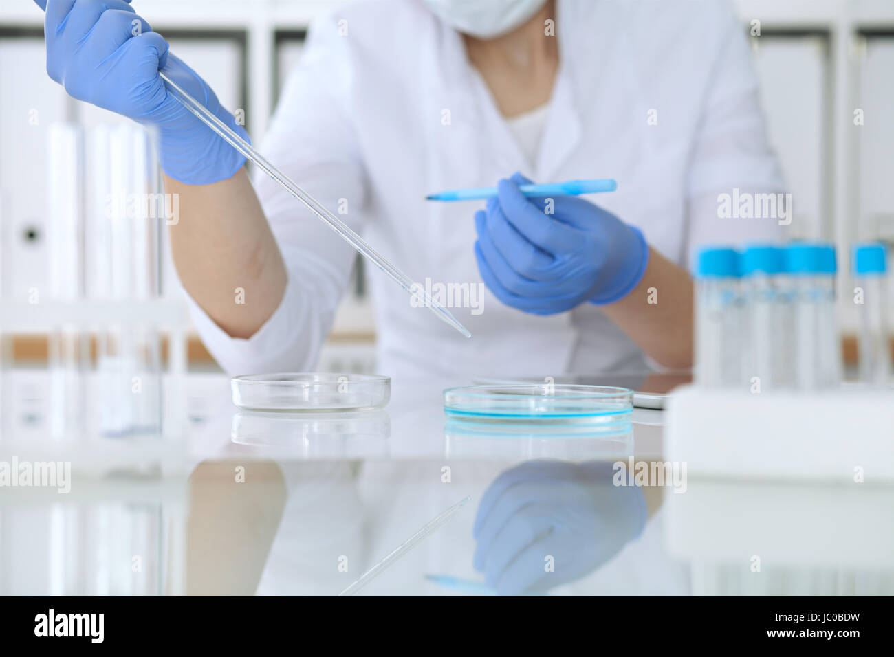 Close up of scientific research hands with clear solution in laboratory ...
