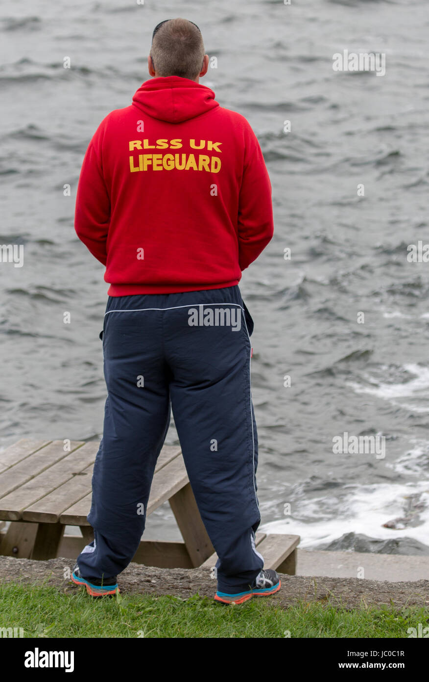 A Royal Life Saving Society Lifeguard looks out across a lake Stock ...