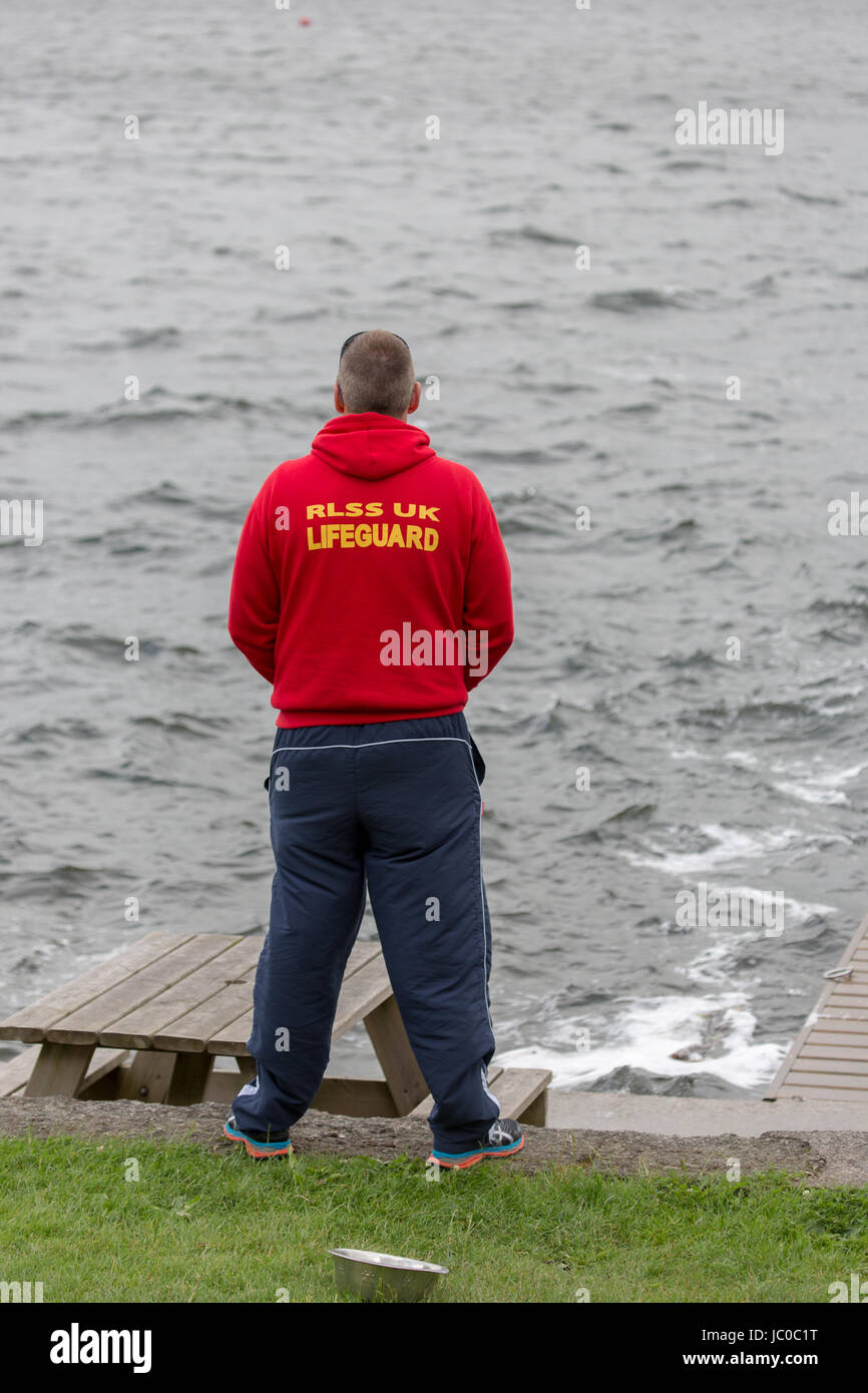 A Royal Life Saving Society Lifeguard looks out across a lake Stock ...